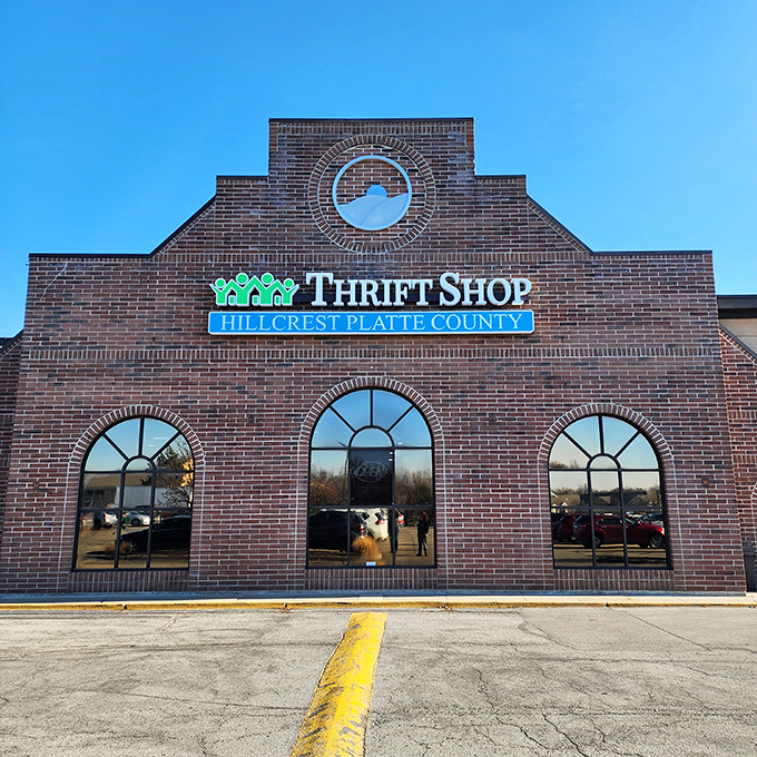 The brick facade of Hillcrest Thrift Shop glows at sunset, its arched windows like welcoming arms saying, "Come find your treasure!"