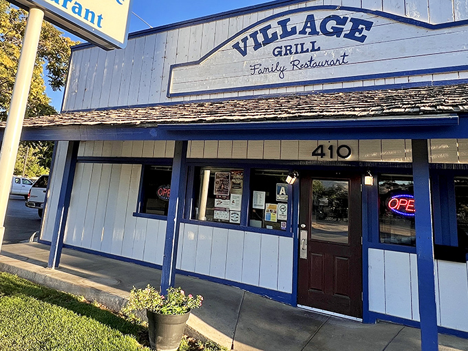 The blue-trimmed exterior of Village Grill stands like a beacon of breakfast hope on Tehachapi Boulevard, promising comfort food salvation to hungry travelers.