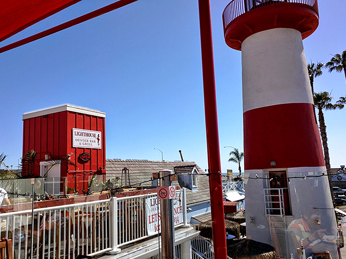 The distinctive red-and-white, lighthouse-style structure of the Lighthouse Oyster Bar & Grill stands as a culinary beacon against the clear blue sky, inviting hungry travelers to discover its fresh seafood delights.