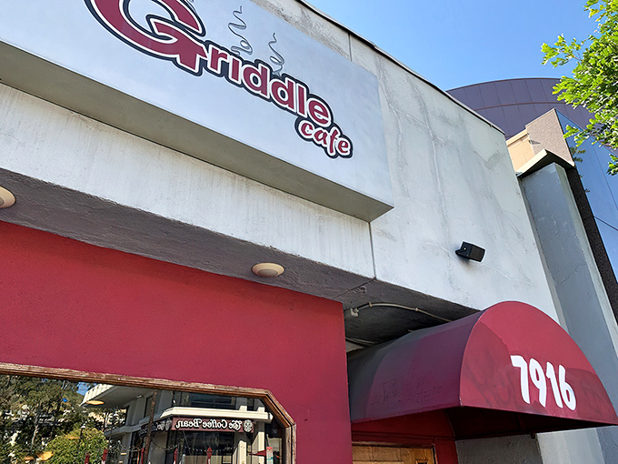 The vibrant red facade of The Griddle Cafe stands out on Sunset Boulevard like a beacon for breakfast enthusiasts. Simple outdoor seating belies the culinary magic happening inside.