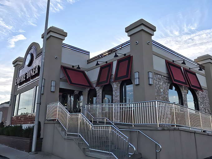 The grand exterior of New Empire Diner stands like a beacon for hungry travelers, its distinctive red awnings and American flag promising classic comfort with a touch of glamour.