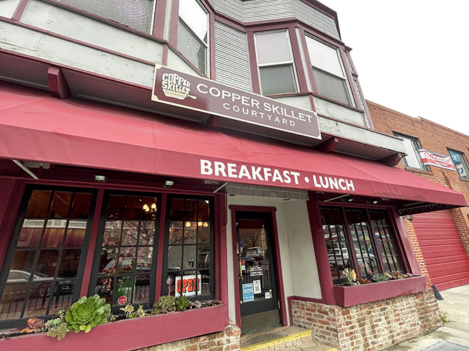 The charming facade of Copper Skillet Courtyard beckons with its distinctive red awning, promising comfort food treasures within this historic Martinez building.