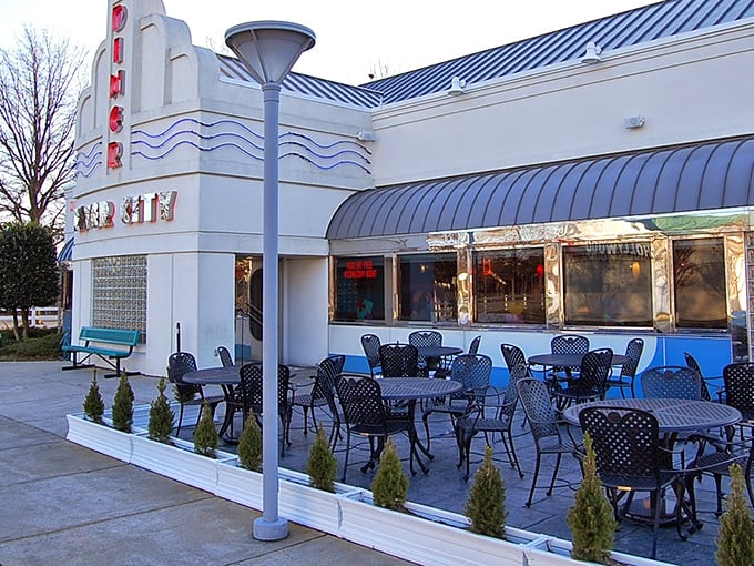 The sleek, retro-modern exterior of River City Diner beckons with its distinctive blue trim and inviting patio seating&mdash;a roadside oasis for hungry travelers.
