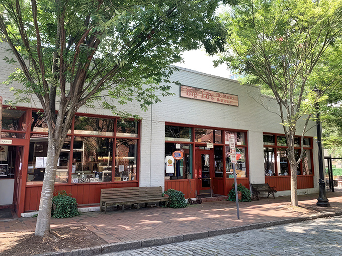 The unassuming white brick exterior of Big Ed's City Market Restaurant, where culinary magic happens behind those red-trimmed windows.