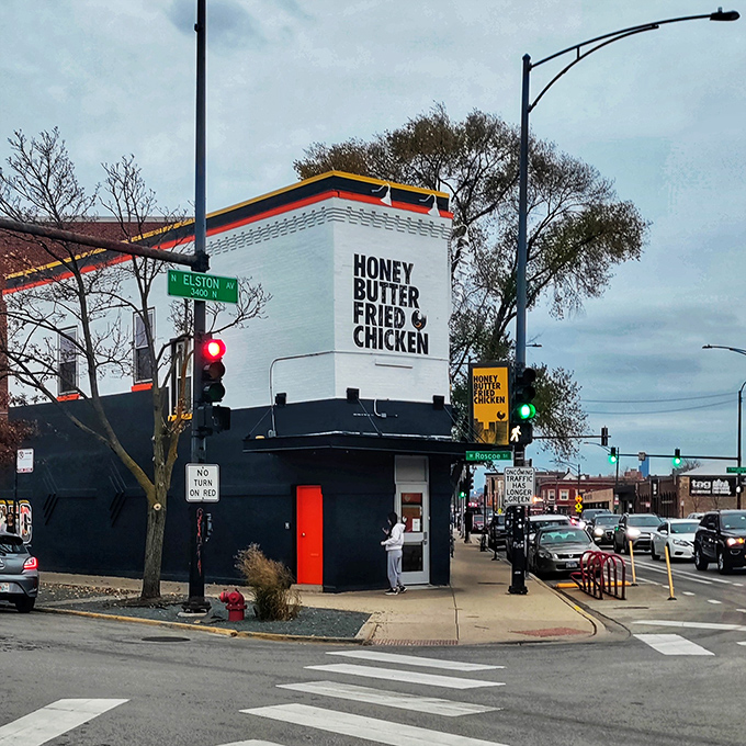 The corner building announces its purpose without pretense. Bold lettering on white brick promises a straightforward mission: chicken that will change your life.