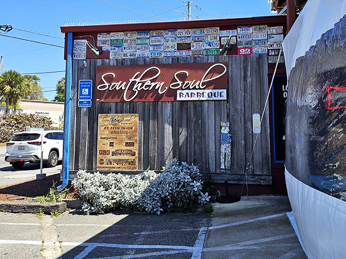 The barbecue promised land awaits behind this weathered wood facade, where license plates from pilgrims past create a roadmap to smoky perfection.