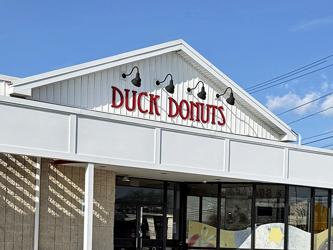 The white facade with bold red lettering promises donut nirvana. Those black lamps aren't just for show &ndash; they're illuminating the path to happiness.