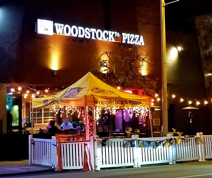 The neon glow of Woodstock's Pizza sign cuts through the night like a beacon for hungry travelers. Pizza paradise awaits.