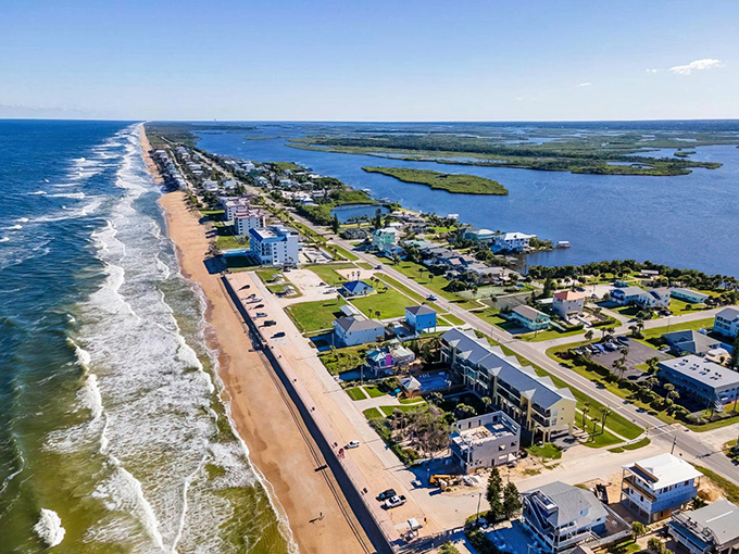 Where ocean meets river in perfect harmony. This aerial view of New Smyrna Beach showcases the narrow barrier island with Atlantic waves on one side, tranquil Intracoastal on the other.