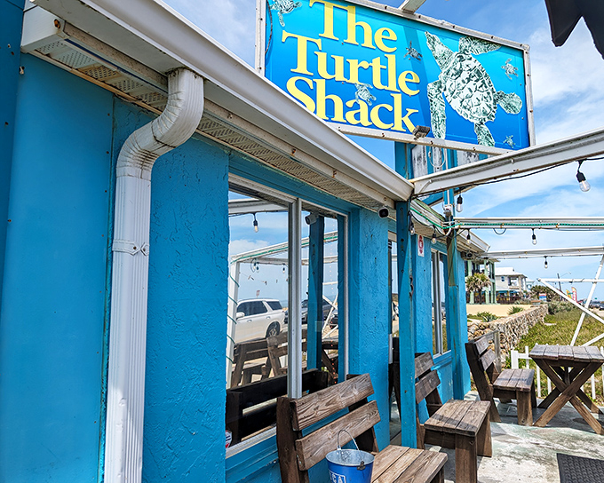 The little blue bungalow that could! Turtle Shack's charming exterior with rustic wooden benches invites you to slow down and savor coastal living at its finest.