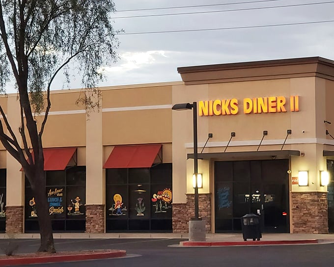 Nick's Diner II announces itself with golden letters against desert beige, those red awnings practically whispering "come in, the air conditioning is glorious."