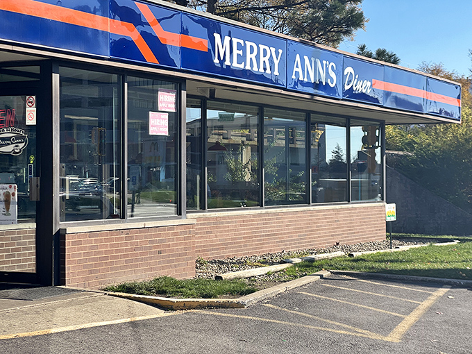 The blue and orange beacon of Merry Ann's Diner glows like a lighthouse for the hungry, promising comfort food salvation at any hour of the night.