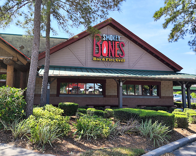 The rustic lodge-style exterior of Smokey Bones stands as a smoky oasis amid Florida's palm trees, promising barbecue salvation to meat lovers seeking refuge from theme park fare.