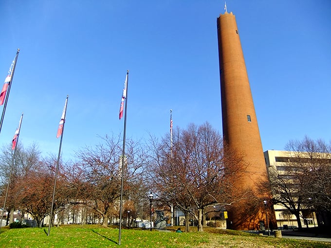 The Phoenix Shot Tower stands like a brick sentinel against Baltimore's blue sky, surrounded by flags that whisper stories of America's industrial past.