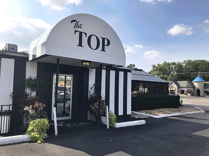 The iconic entrance to The Top Steak House stands like a mid-century modern time portal, beckoning carnivores with its bold geometric awning and unmistakable confidence.