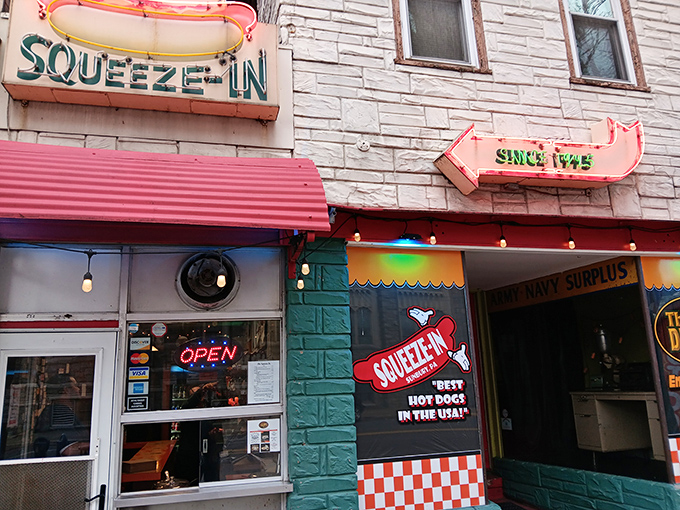 The iconic neon hot dog sign beckons hungry travelers like a lighthouse for comfort food enthusiasts. This sliver of culinary paradise proves good things come in small packages.