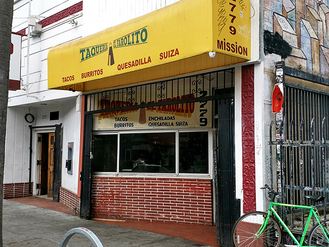 The unassuming yellow storefront of El Farolito stands like a beacon of burrito brilliance on Mission Street, complete with its signature green bicycle sentinel.