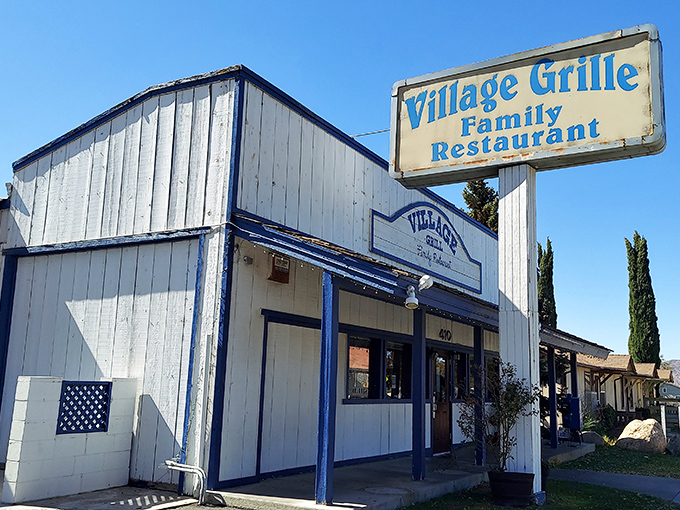 The blue-trimmed exterior of Village Grill stands like a beacon of breakfast hope on Tehachapi Boulevard, promising comfort food salvation to hungry travelers.