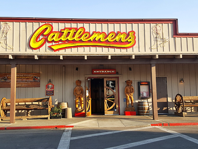 The iconic yellow Cattlemens sign welcomes hungry travelers like a beacon of beef-related bliss. Those wooden cowboys aren't just decorative&mdash;they're promising you the steak of your dreams.