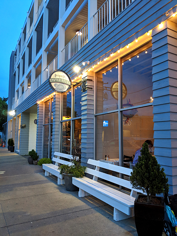 The evening glow transforms Henlopen City Oyster House into a beacon for seafood lovers, with string lights promising culinary magic within those white-sided walls.