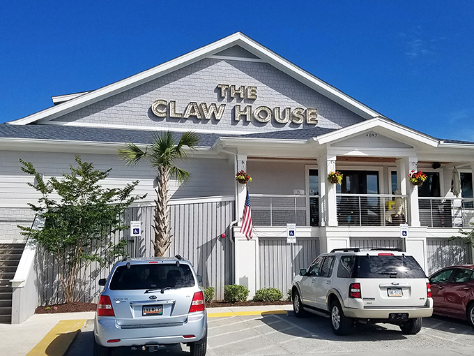 The coastal charm of The Claw House beckons seafood lovers with its classic gray and white exterior. A palm tree stands guard, promising a taste of Maine in Murrells Inlet.
