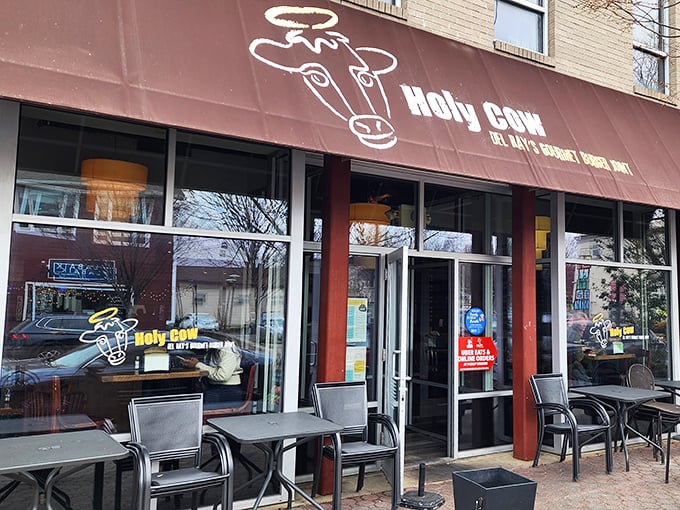 Holy Cow's inviting storefront in Del Ray beckons burger enthusiasts with its simple maroon awning and heavenly bovine logo—a preview of the divine experience within.