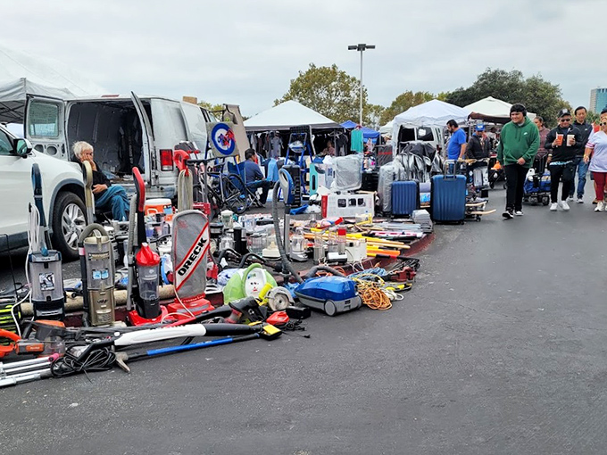 Treasure hunting begins under blue canopies where sports jerseys hang like championship banners above tables of potential finds.