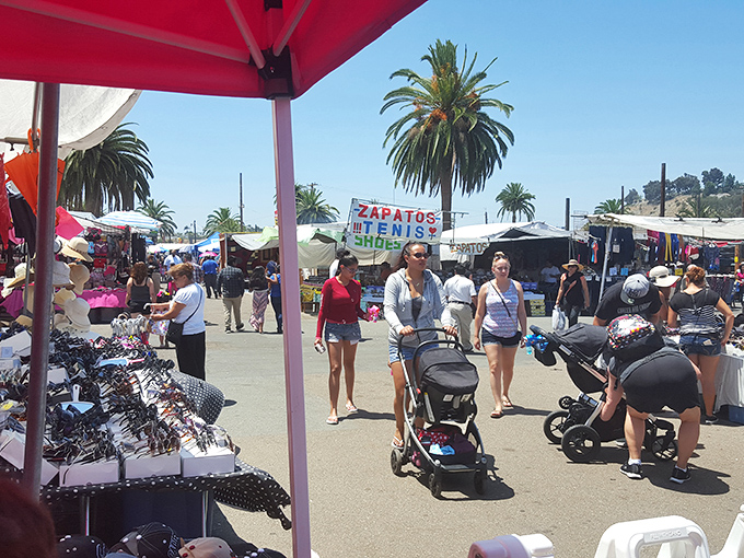 Palm trees stand sentinel over a bustling marketplace where shoppers navigate stalls of treasures under the California sun.