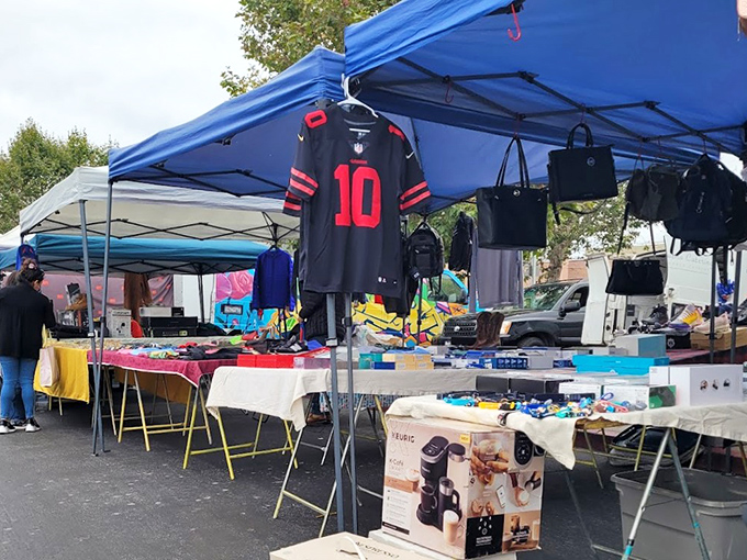 Treasure hunting begins under blue canopies where sports jerseys hang like championship banners above tables of potential finds.