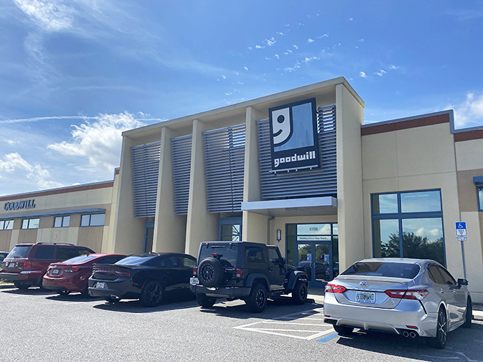 The modern exterior of Goodwill Goldenrod stands like a beacon of bargain hope under Florida's impossibly blue sky, promising air-conditioned treasure hunting inside.