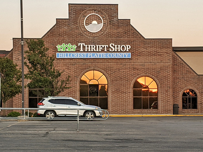 The brick facade of Hillcrest Thrift Shop glows at sunset, its arched windows like welcoming arms saying, "Come find your treasure!"