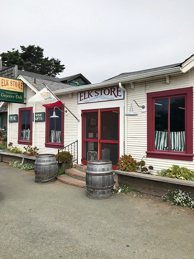 The quintessential coastal discovery: Elk Store's charming white clapboard exterior with burgundy trim and wooden barrels promises treasures that chain stores can't deliver.