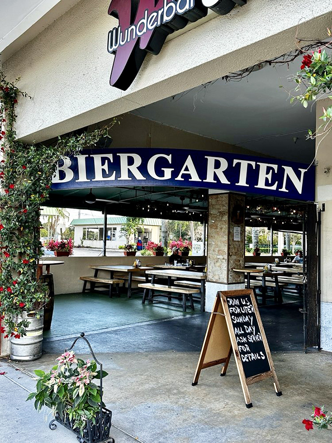 The inviting entrance to Wunderbar beckons with its vibrant blue "BIERGARTEN" sign and climbing vines&mdash;Bavaria's warm embrace in sunny Florida.