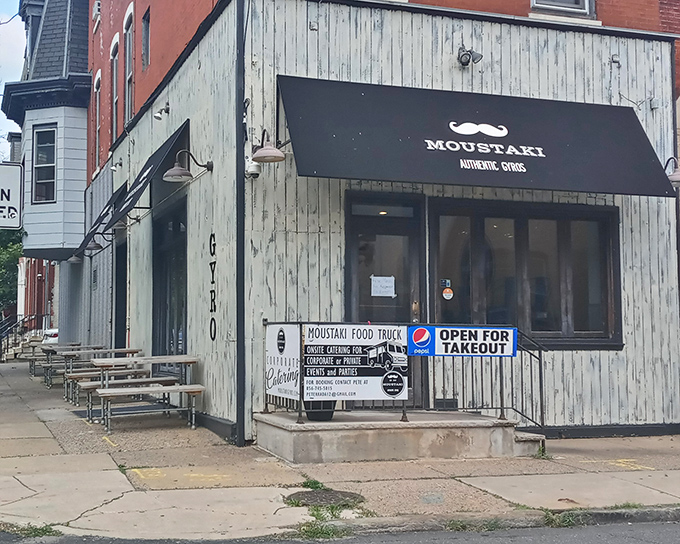 The unassuming storefront with its playful mustache logo promises Greek treasures within. Sometimes the most memorable meals hide behind the simplest facades.