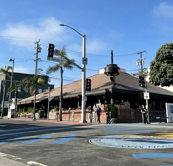 The iconic sloped roof and palm trees of The Kettle stand sentinel at Manhattan Beach's busiest corner, beckoning hungry souls like a culinary lighthouse.