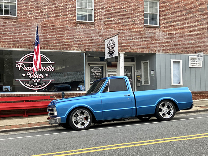The classic American diner dream comes to life in brick and mortar, complete with that inviting red bench where friendships are forged while waiting for tables.