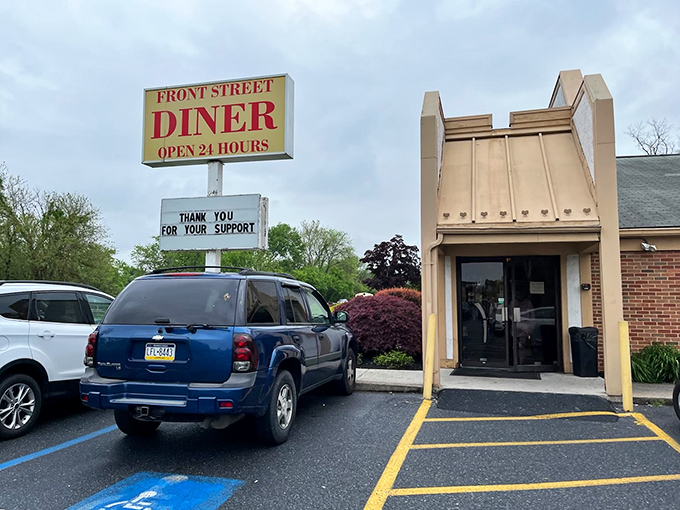 The classic white exterior with its striped awning and "OPEN 24 HOURS" sign stands as a beacon of hope for hungry travelers at any hour.