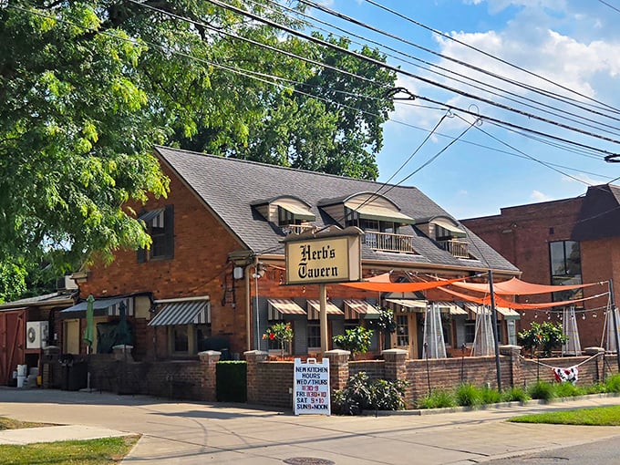 The charming brick exterior of Herb's Tavern, with its distinctive dormered windows, looks like a storybook cottage that happens to serve legendary burgers.