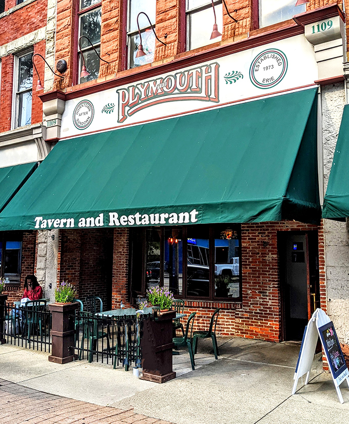 The brick façade of Plymouth Tavern stands proudly on Erie's State Street, a three-story testament to timeless hospitality that beckons hungry travelers inside.