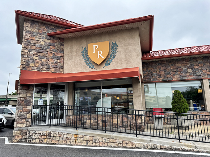 The iconic stone facade and red roof of Penrose Diner stands like a culinary lighthouse, beckoning hungry travelers with its distinctive "PR" shield logo.