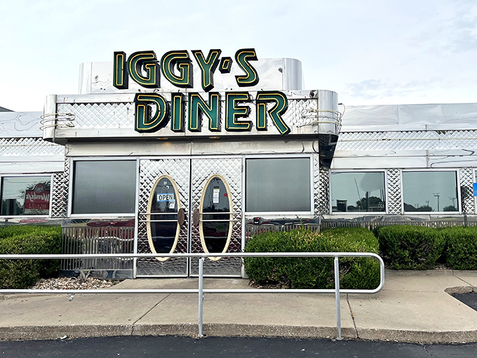 The gleaming silver exterior of Iggy's Diner shines like a time machine to the golden age of Route 66, complete with those iconic oval doors beckoning hungry travelers inside.