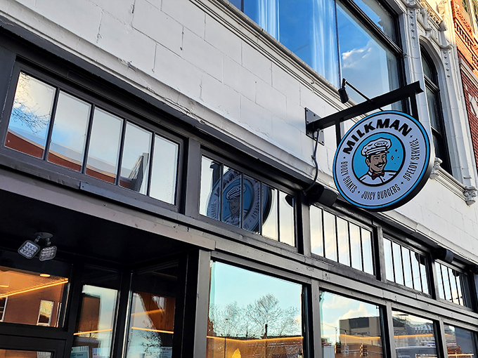 The iconic blue Milkman sign beckons like a lighthouse for the hungry, promising juicy burgers and creamy shakes in Cincinnati's urban landscape.