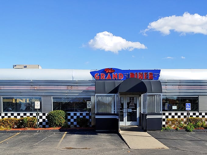 The gleaming stainless steel exterior of The Grand Diner stands like a time capsule on wheels, complete with that iconic checkered trim that promises nostalgic delights inside.
