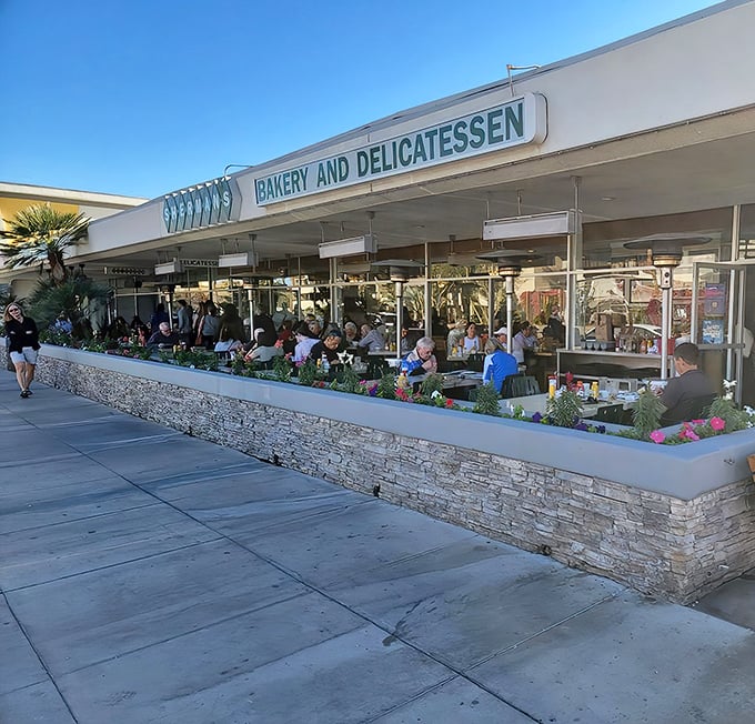 The desert sun gleams off Sherman's iconic white exterior and green diamond logo, a Palm Springs landmark promising deli delights within.