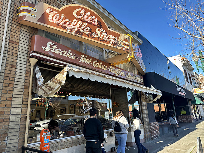 The iconic neon sign of Ole's Waffle Shop glows like a breakfast beacon on Alameda's Park Street, promising comfort food salvation to hungry souls.