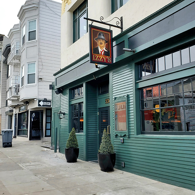 The iconic green exterior of Izzy's with its distinctive fedora-wearing man sign stands as a beacon of old-school steakhouse tradition in San Francisco.