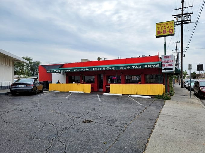 The bright red exterior of Swinging Door BBQ stands out like a beacon of hope for hungry travelers. Those wagon wheels aren't just for show&mdash;they're rolling you toward flavor town.