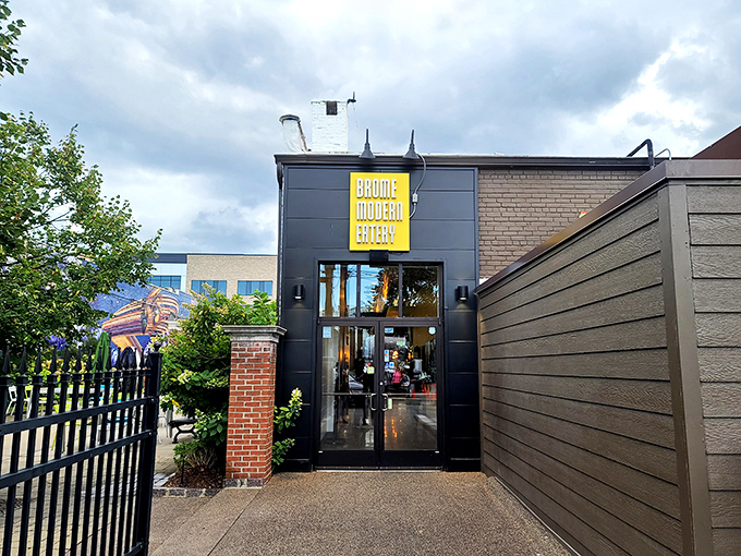 The sleek exterior of Brome Modern Eatery beckons with its bold yellow signage against dark walls&mdash;like a culinary lighthouse guiding hungry Michiganders home.