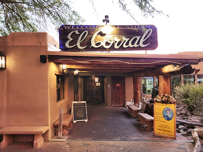The iconic entrance to El Corral welcomes diners with rustic Southwestern charm, saguaro sentinels, and the promise of mesquite-grilled perfection.