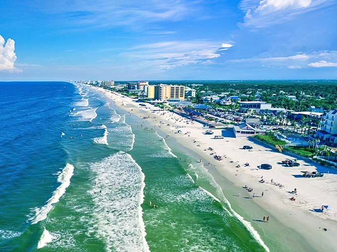 Where ocean meets river in perfect harmony. This aerial view of New Smyrna Beach showcases the narrow barrier island with Atlantic waves on one side, tranquil Intracoastal on the other.
